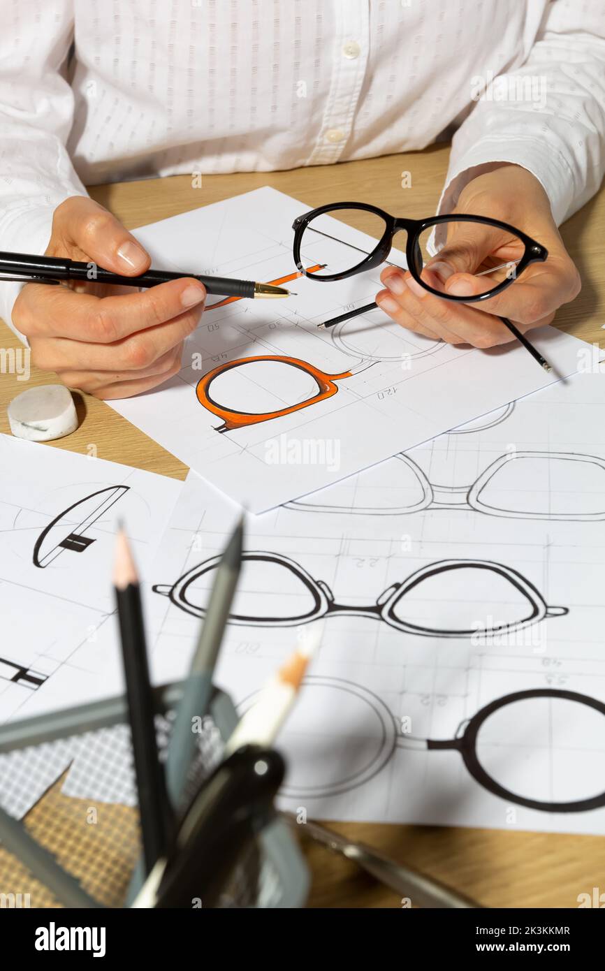 The designer draws a sketch of eyeglasses on paper. Creating glasses ...