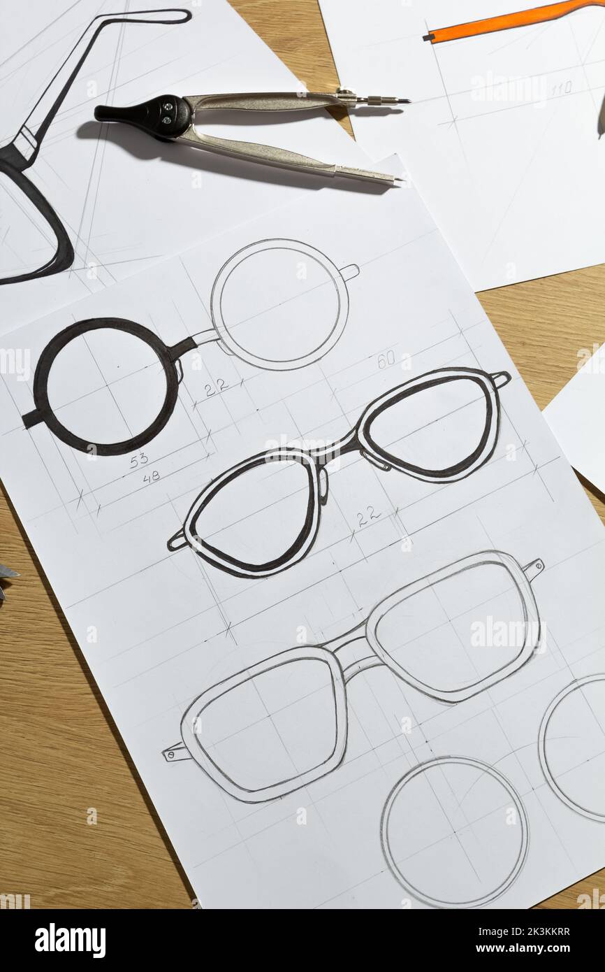 The designer draws a sketch of eyeglasses on paper. Creating glasses ...