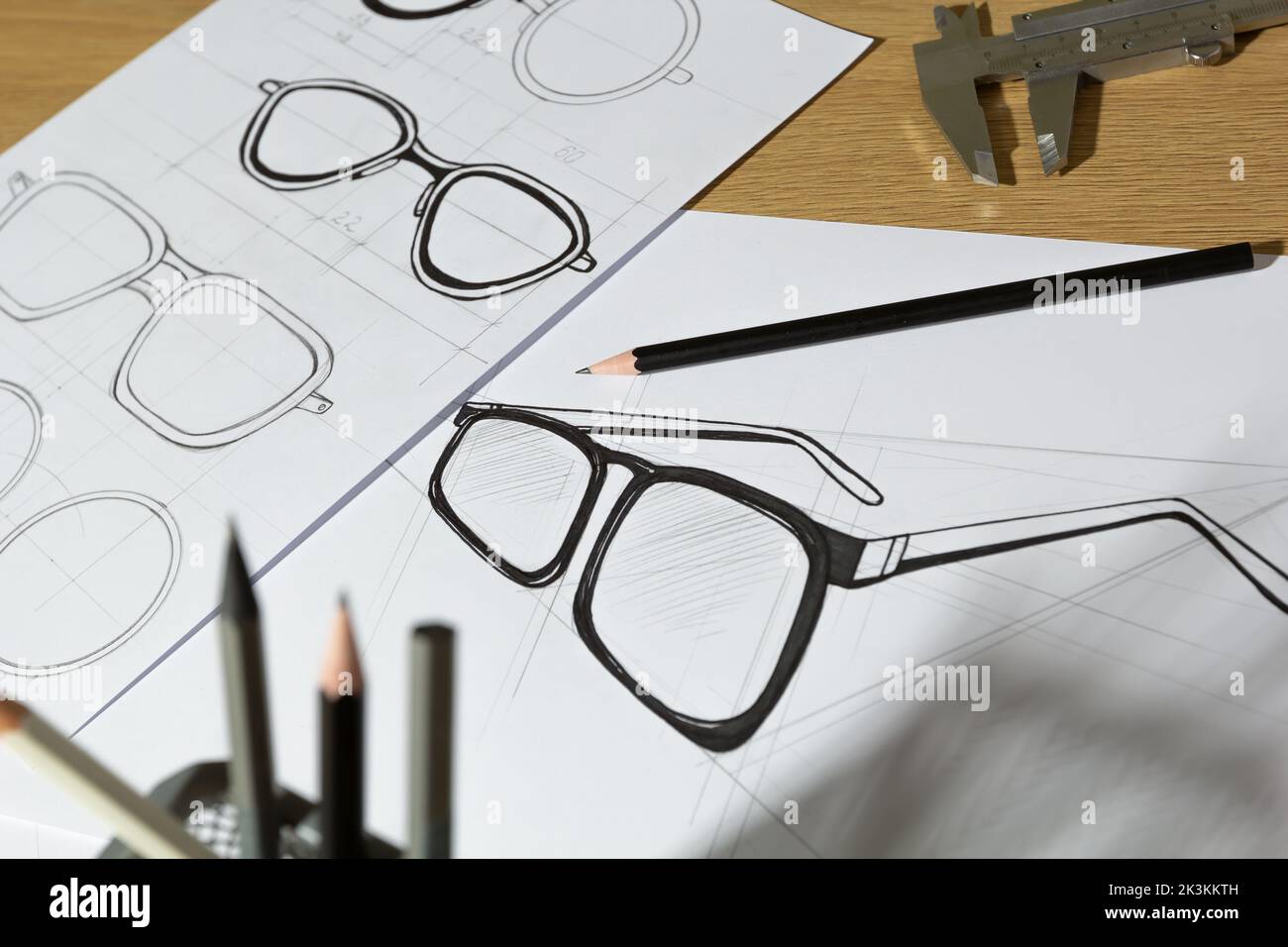 The designer draws a sketch of eyeglasses on paper. Creating glasses ...