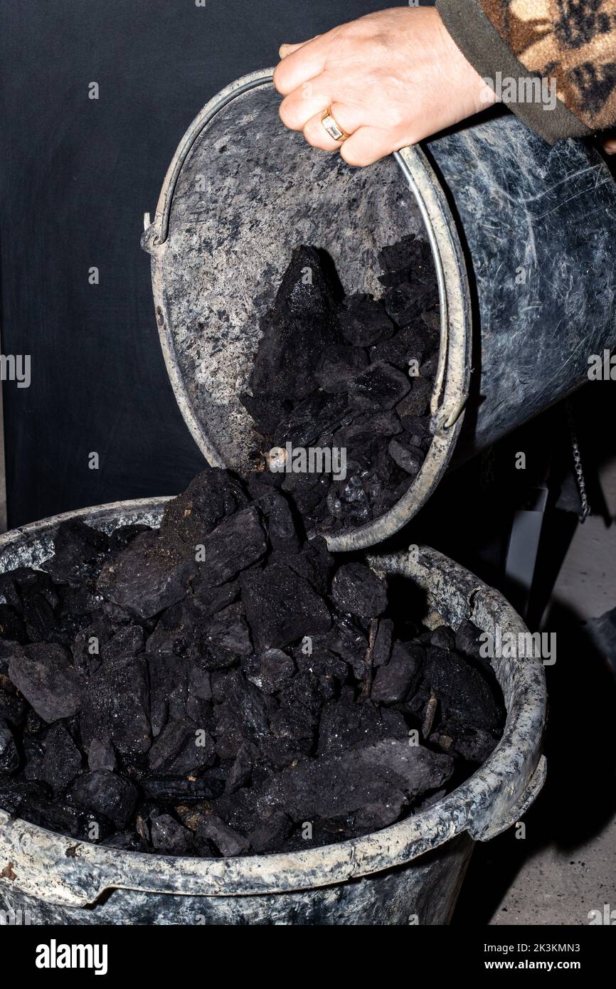 A man pours coal into a bucket. Fuel for heating a private house Stock ...