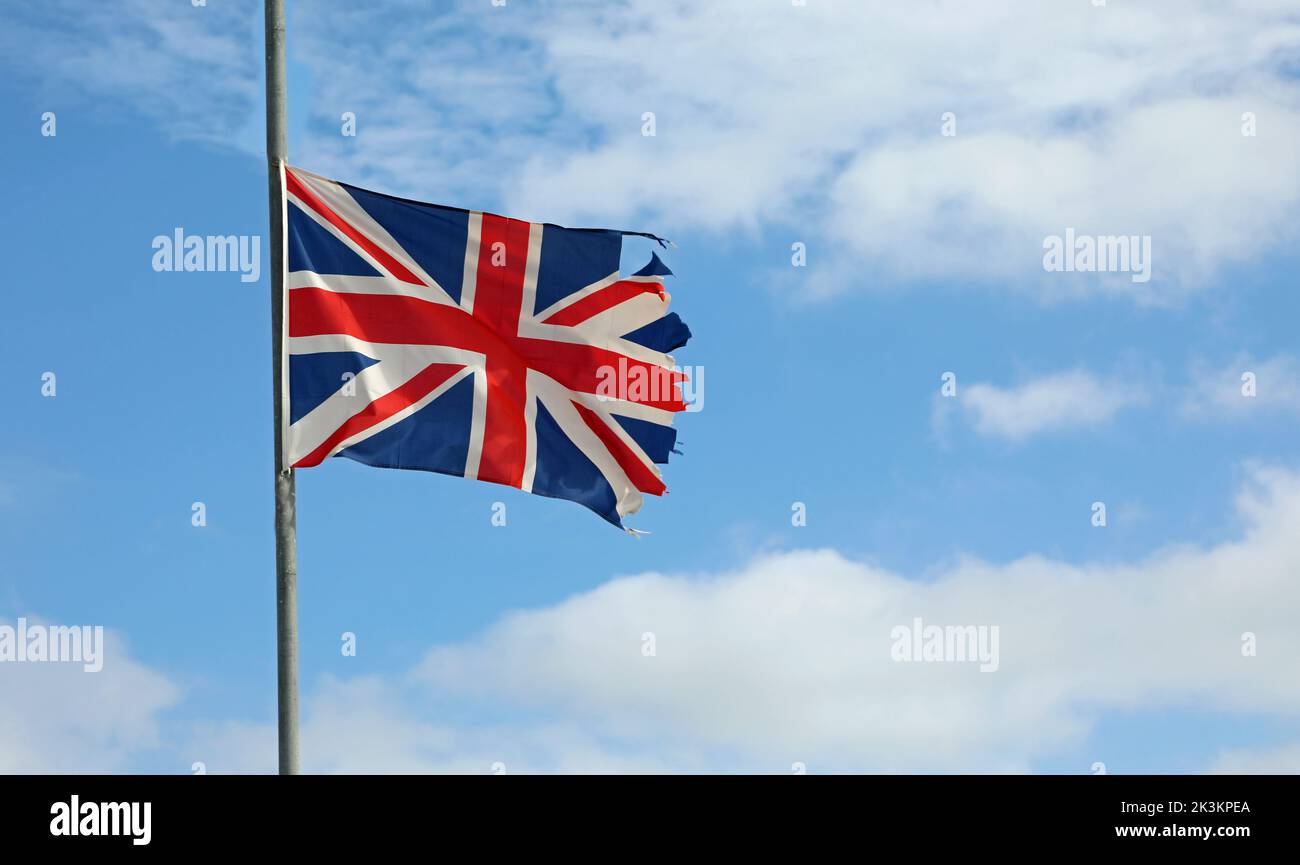 frayed English flag at half mast all ruined due to bad weather Stock ...