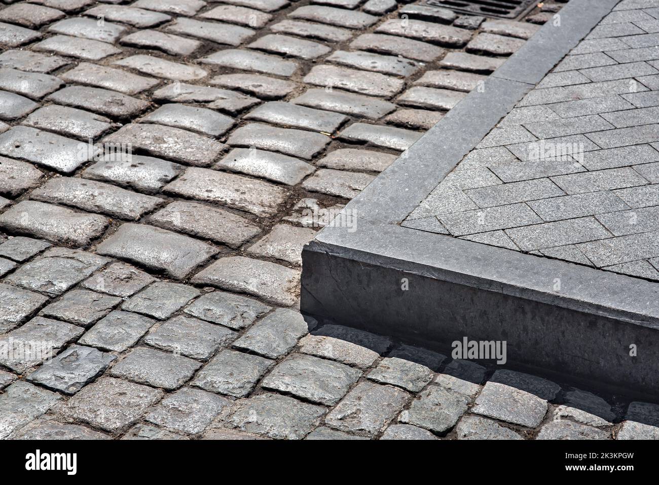 The corner of the sidewalk made of stone tiles with access to the road ...