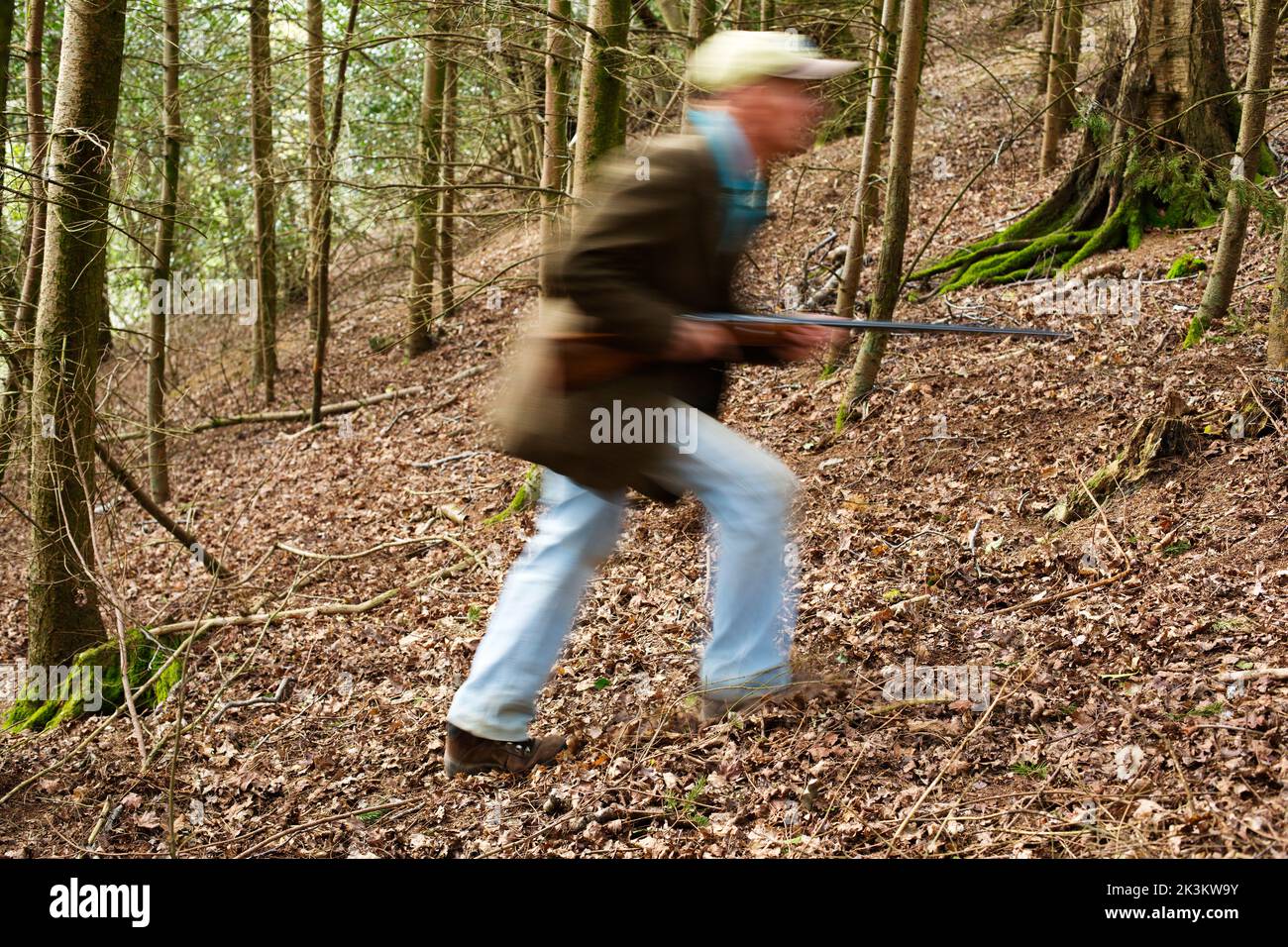 A blury image of a man walking through woods woth a gun Stock Photo - Alamy