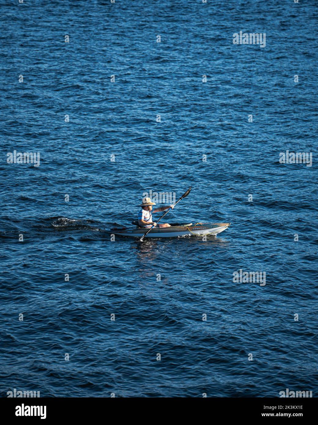 A vertical shot of a man kayaking on blue ocean water waves in Seattle ...