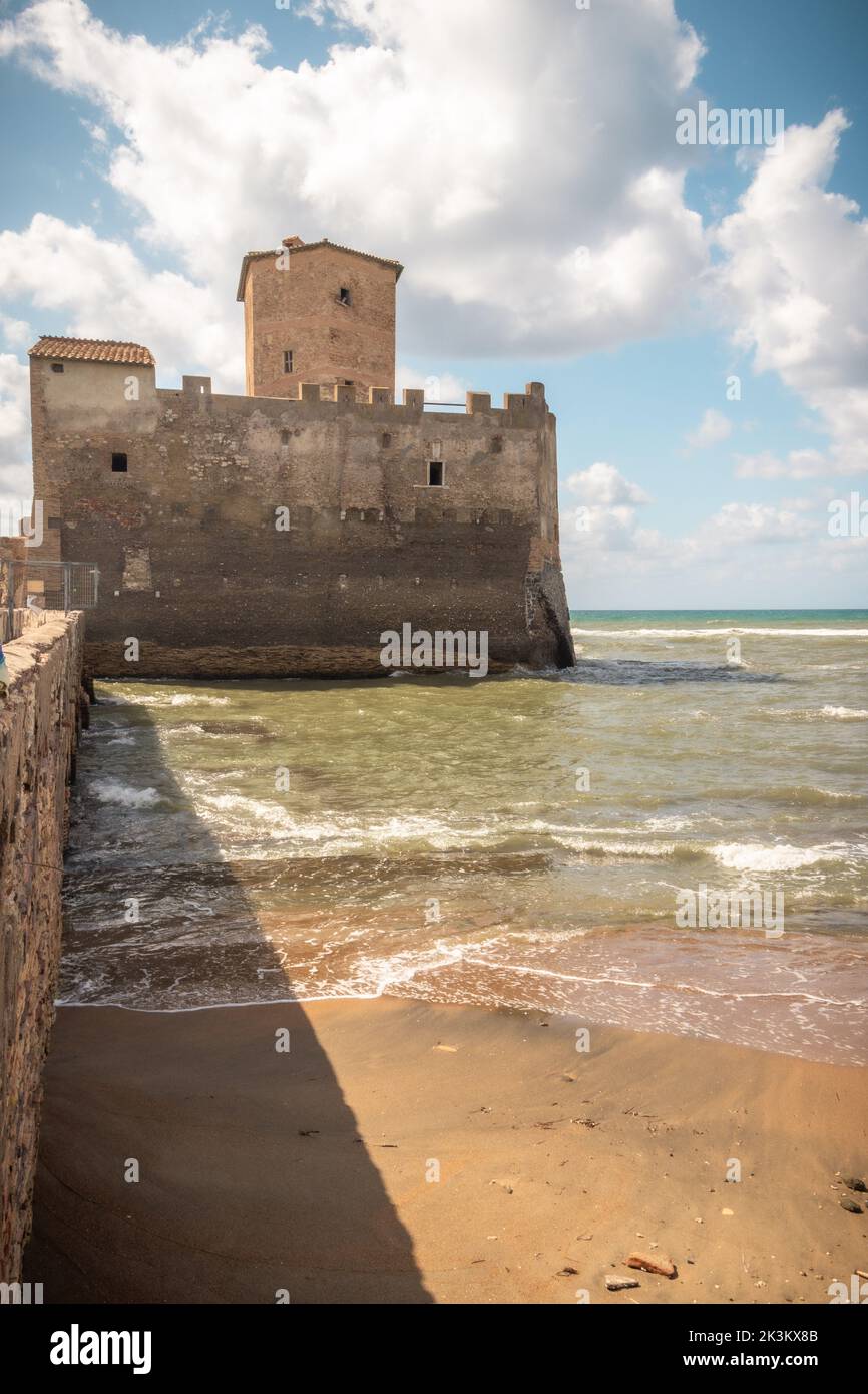 waves splash on the beach in front of the castle Torre Astura, Rome ...