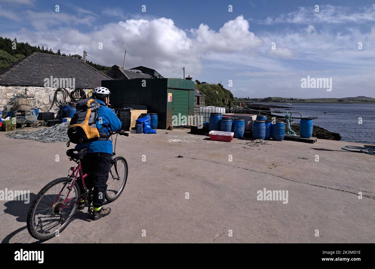 A female cyclist on her bike at the pier near Dunvegan House, Isle of ...