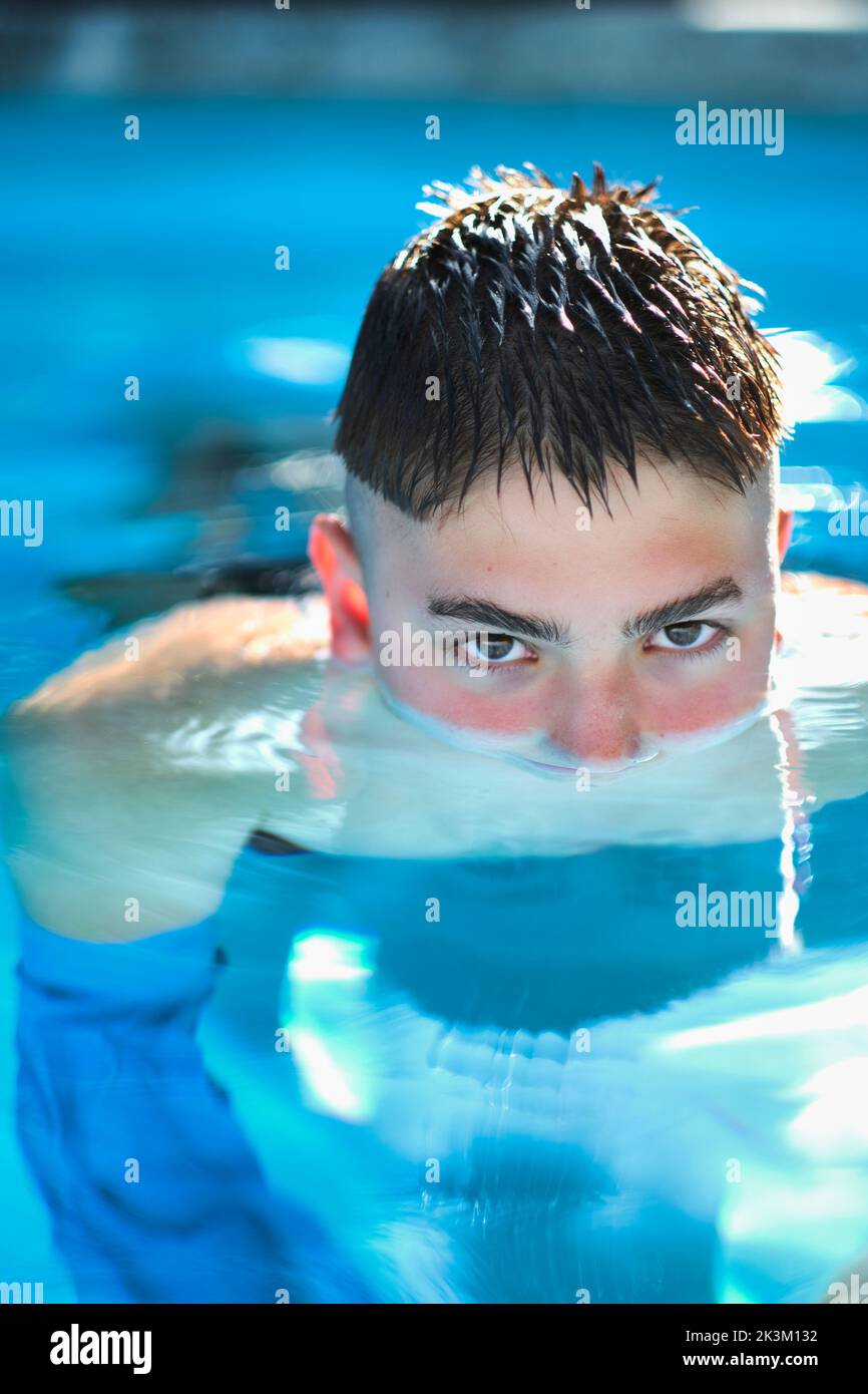 Portrait of a young caucasian boy inside a swimming pool, submerged in ...