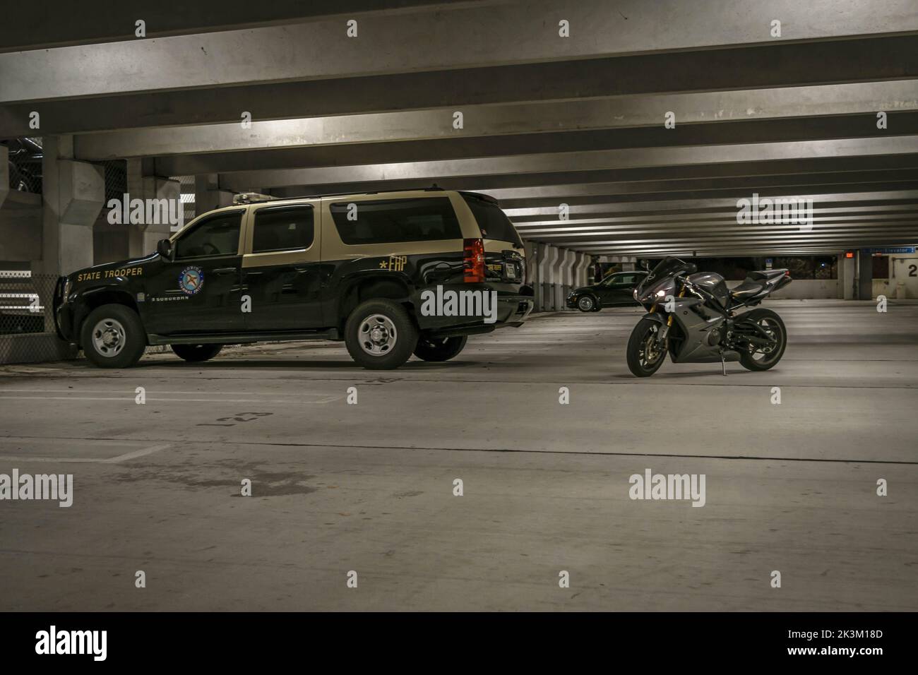 A state trooper police car and a motorcycle in an underground parking ...