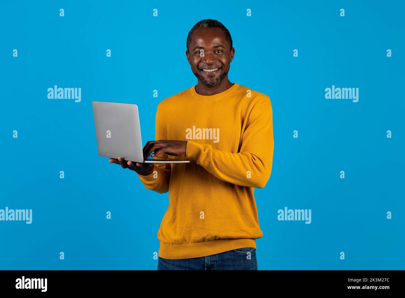 Happy african american man using computer on blue Stock Photo - Alamy