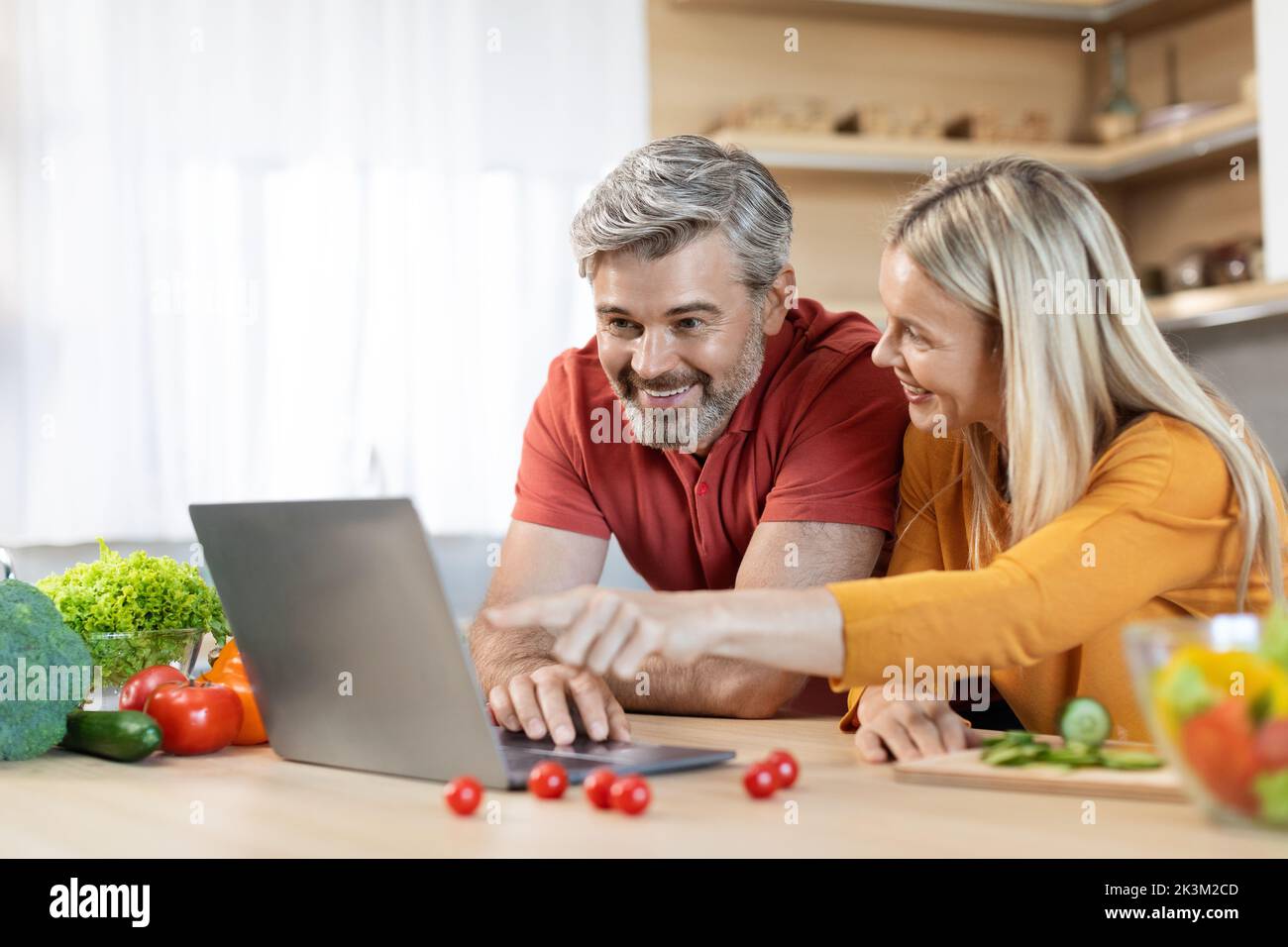 Happy middle aged spouses cooking together, reading food blog Stock ...