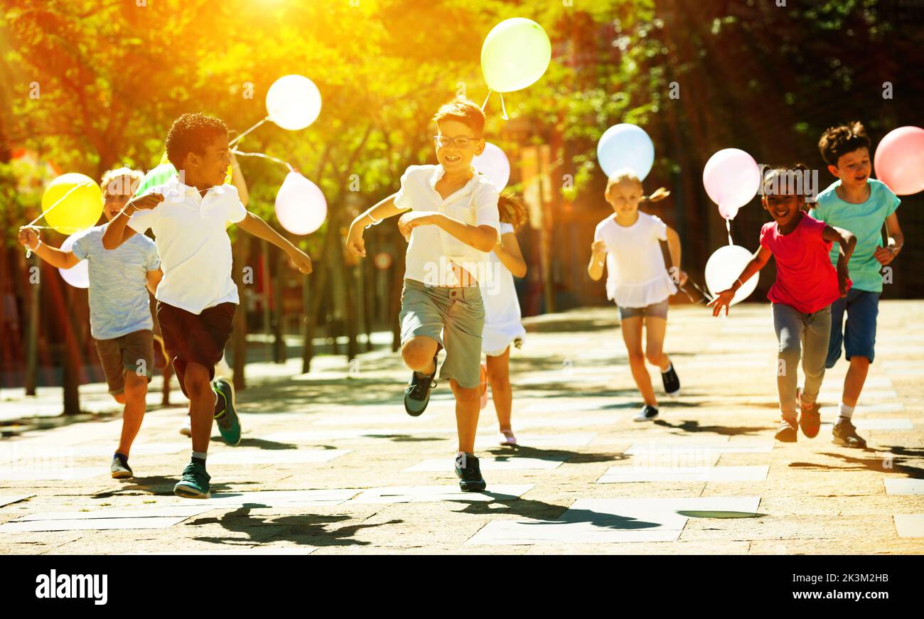 Happy children with balloons run on the summer city street Stock Photo ...