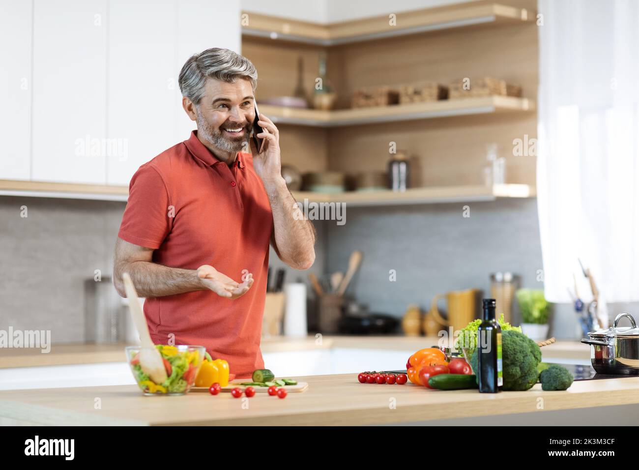 Cheerful grey-haired man inviting his friends for dinner Stock Photo ...