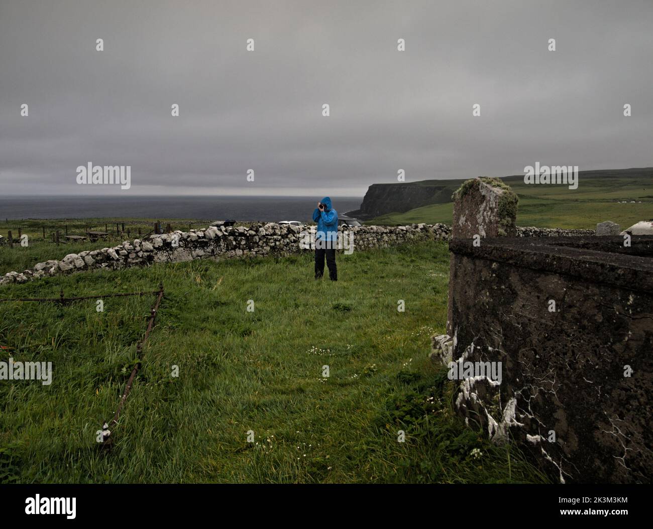 A female photographer at the ruined church at Trumpan, site of the ...