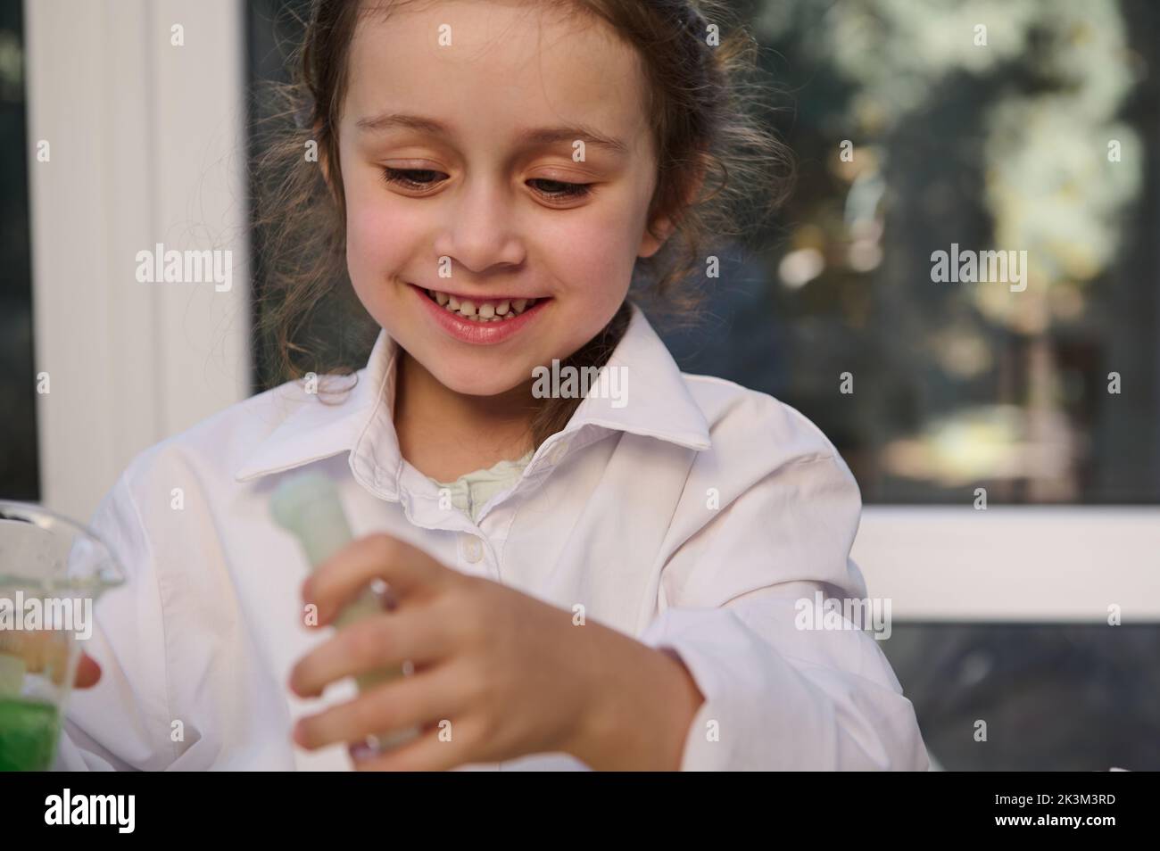 Cute little girl holds laboratory test tube and flask with chemicals ...