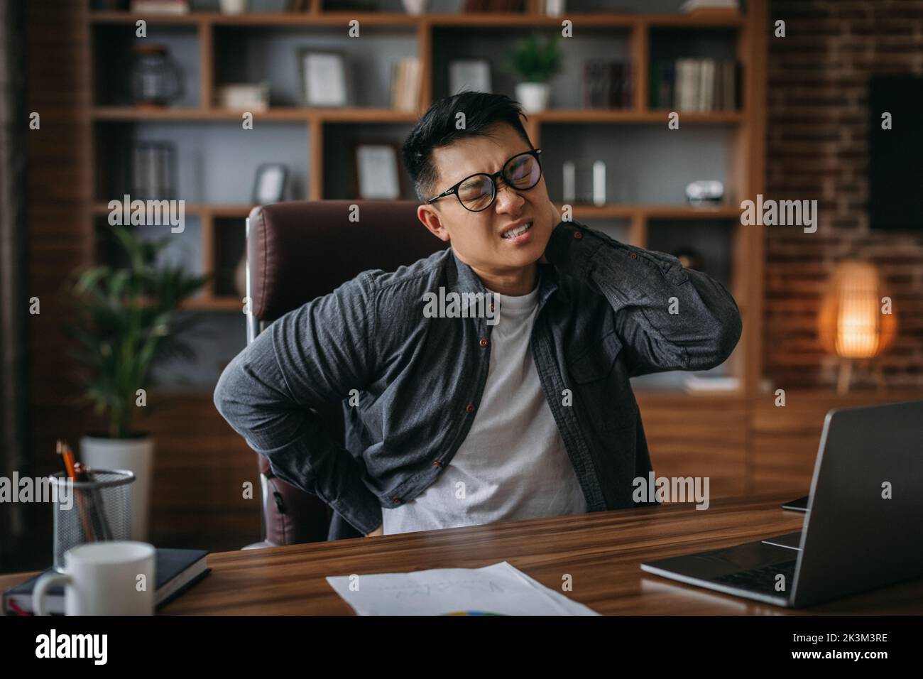 Tired adult japanese man in glasses suffering from long sitting in ...