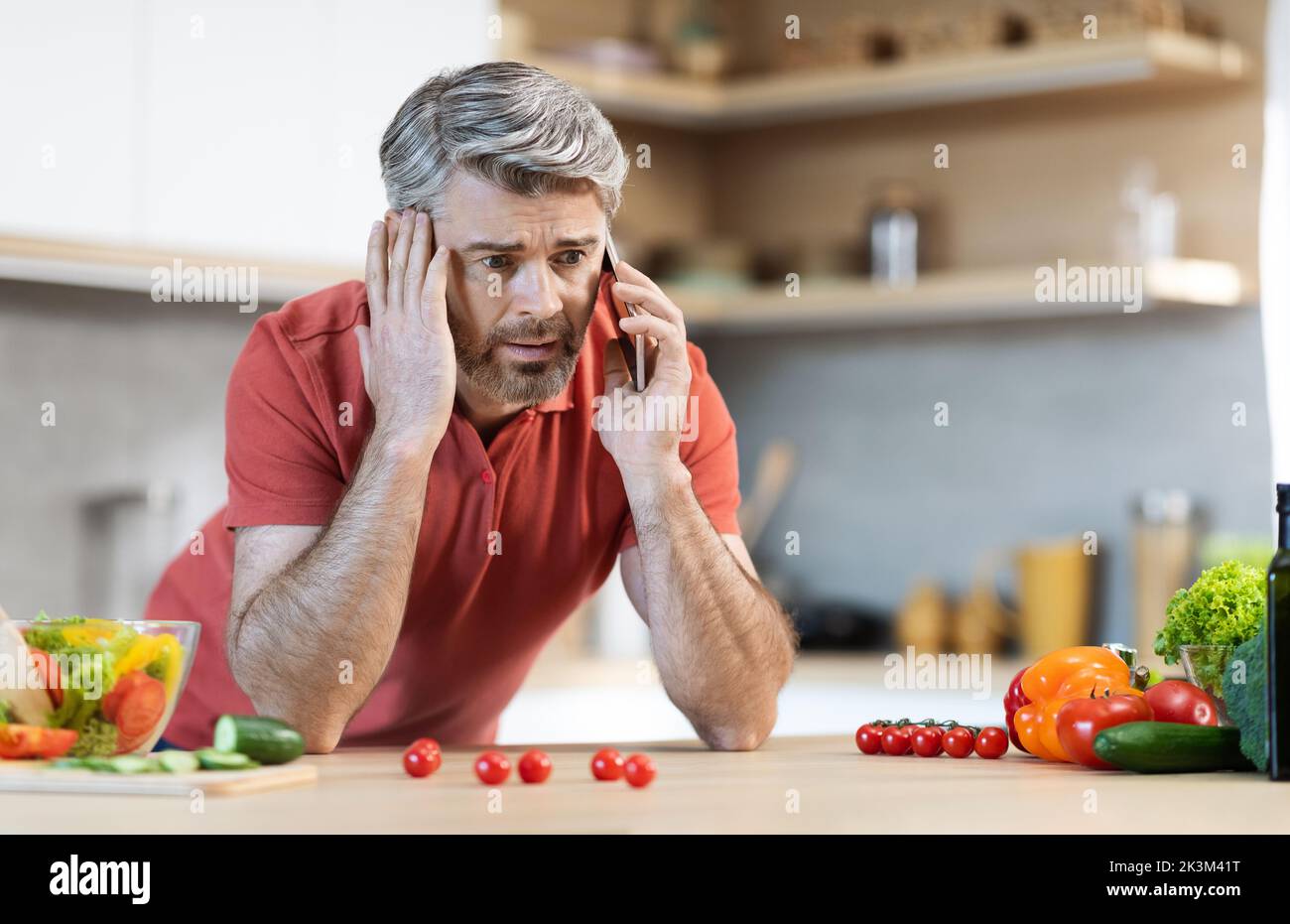 Stressed middle aged man having phone conversation while cooking Stock ...