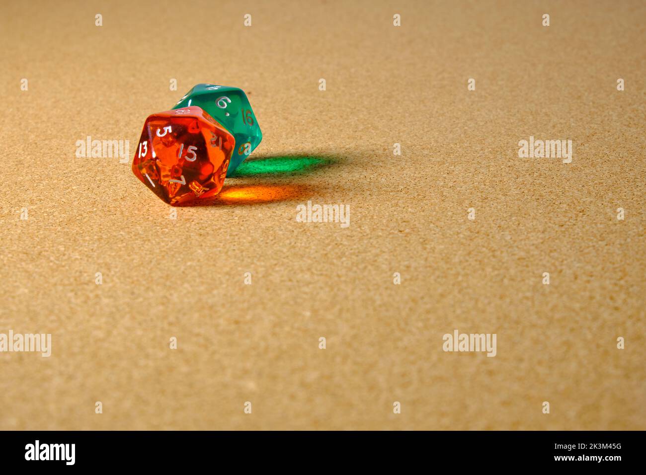 Two transparent d20 dice, one red and one green that have a reflection ...