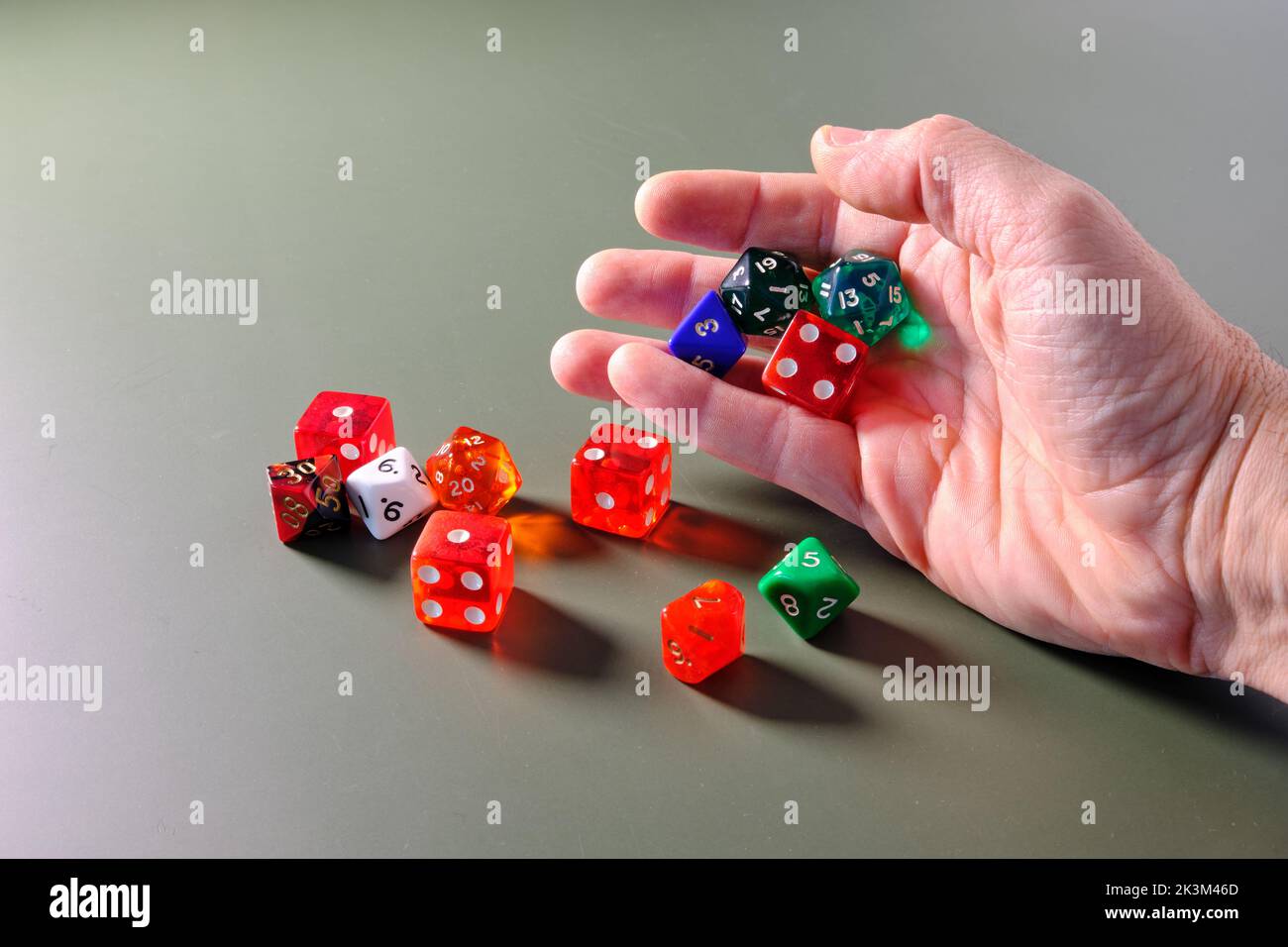 Man's hand picking up different dice to throw them Stock Photo - Alamy