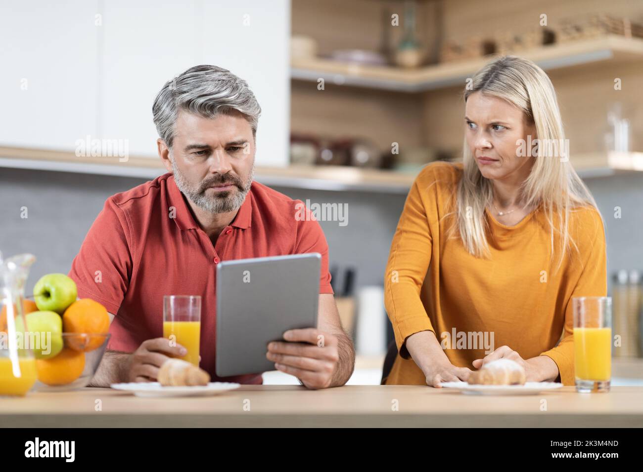 Suspicious wife watching her husband using digital tablet Stock Photo ...