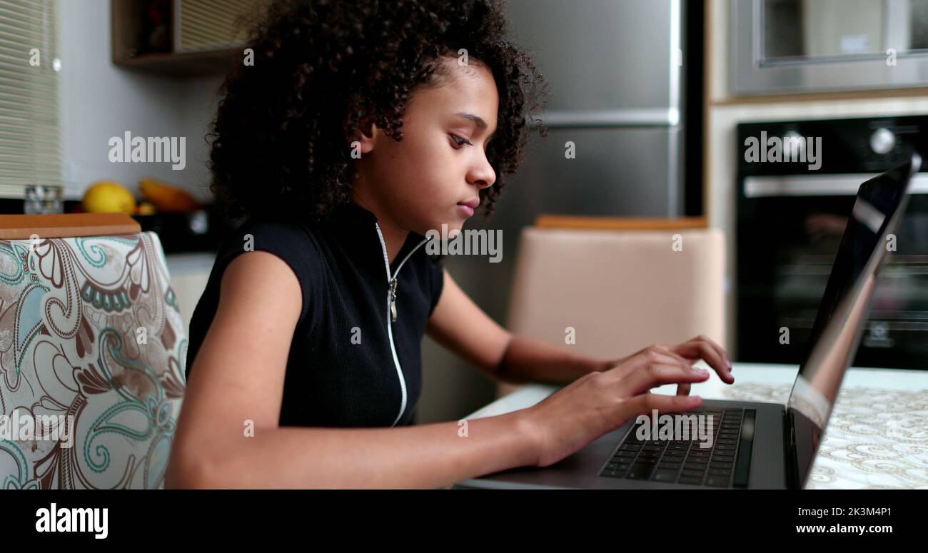 Preteen girl using laptop at home. Black child typing on computer Stock ...