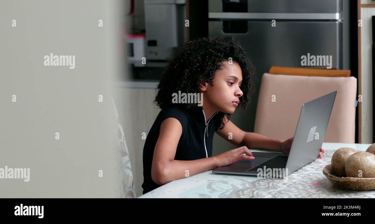 Preteen girl using laptop at home. Black child typing on computer Stock ...