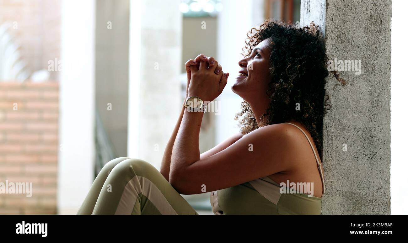 Spiritual woman praying to God in desperate times smiling with HOPE and ...