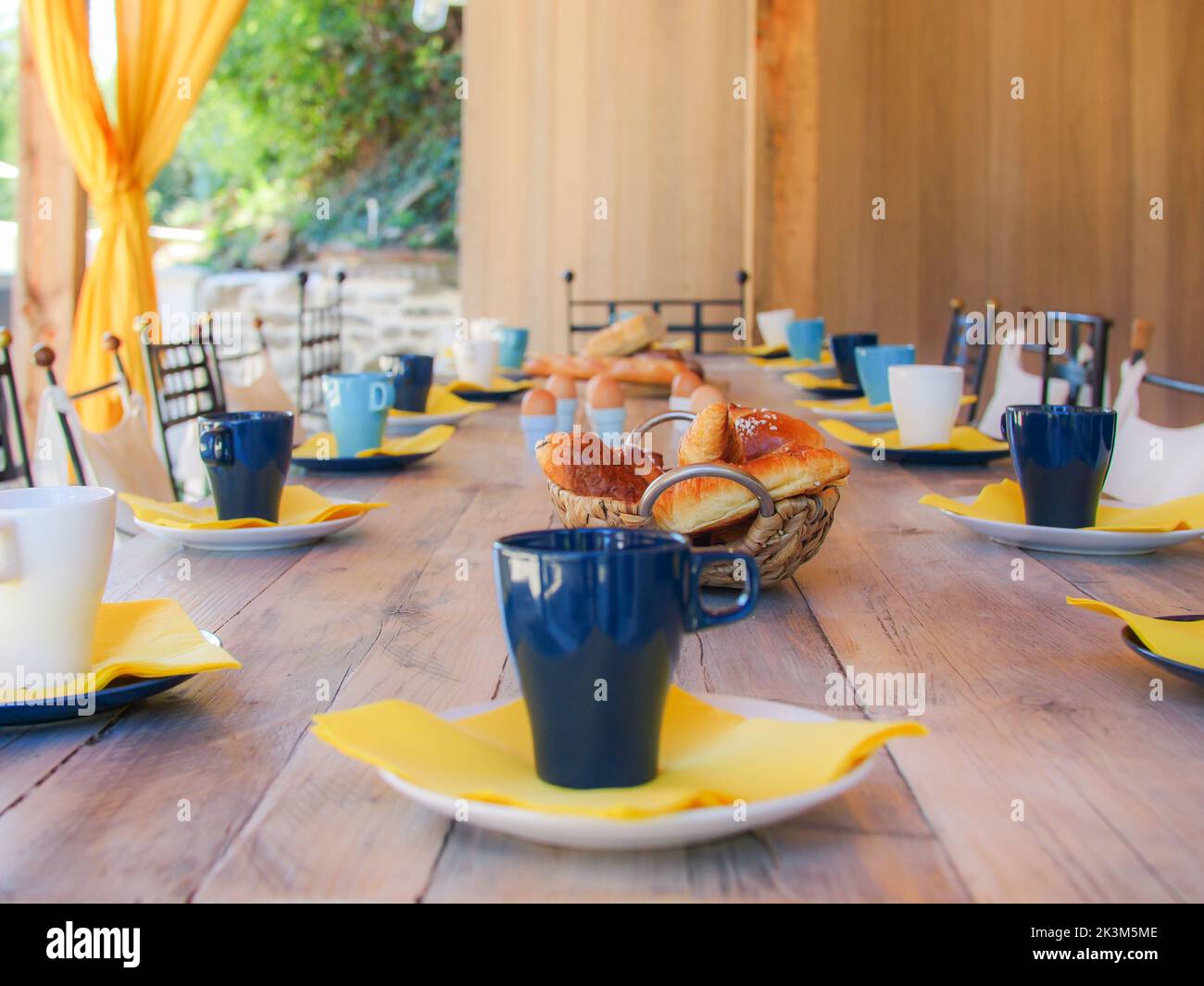 A wooden table set for morning breakfast with plates, blue and white ...