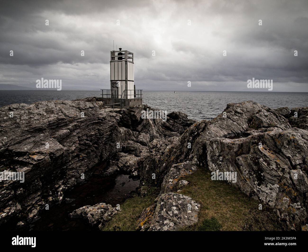 The lighthouse with concrete path running through folded rocks at the ...