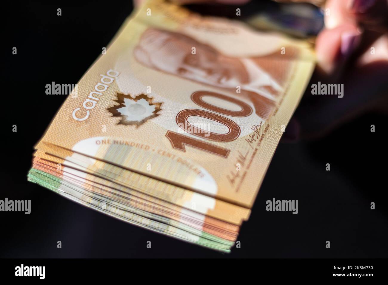 A closeup of stack of Canadian paper money with 100 dollar on the top ...