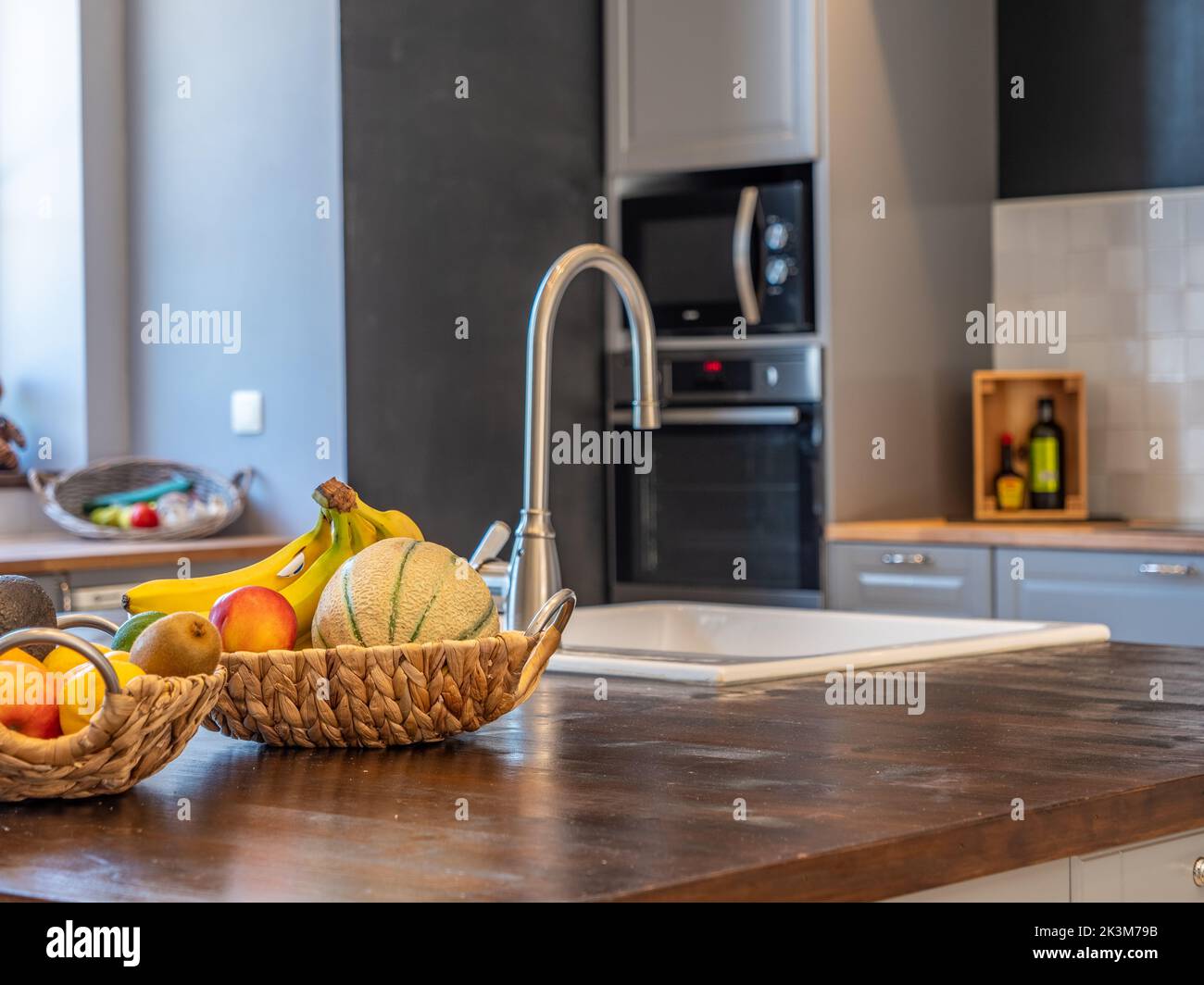 A wooden kitchen island table with a faucet and bowls of fruits Stock ...