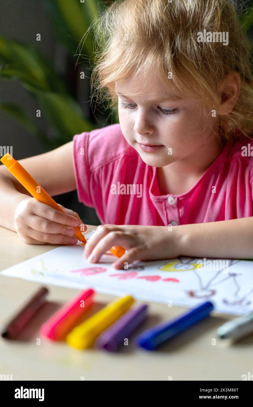 Child drawing a picture of her family with colored markers. Little girl ...