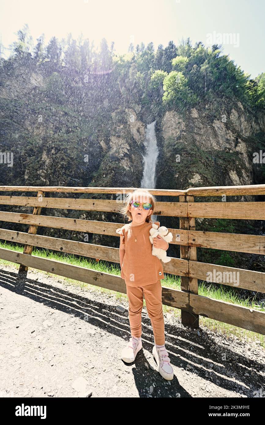 Funny baby girl in sunglasses against waterfall in Liechtensteinklamm ...