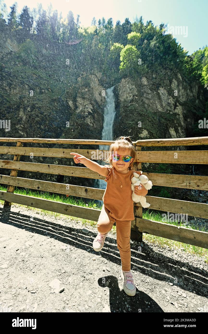 Funny baby girl in sunglasses against waterfall in Liechtensteinklamm ...