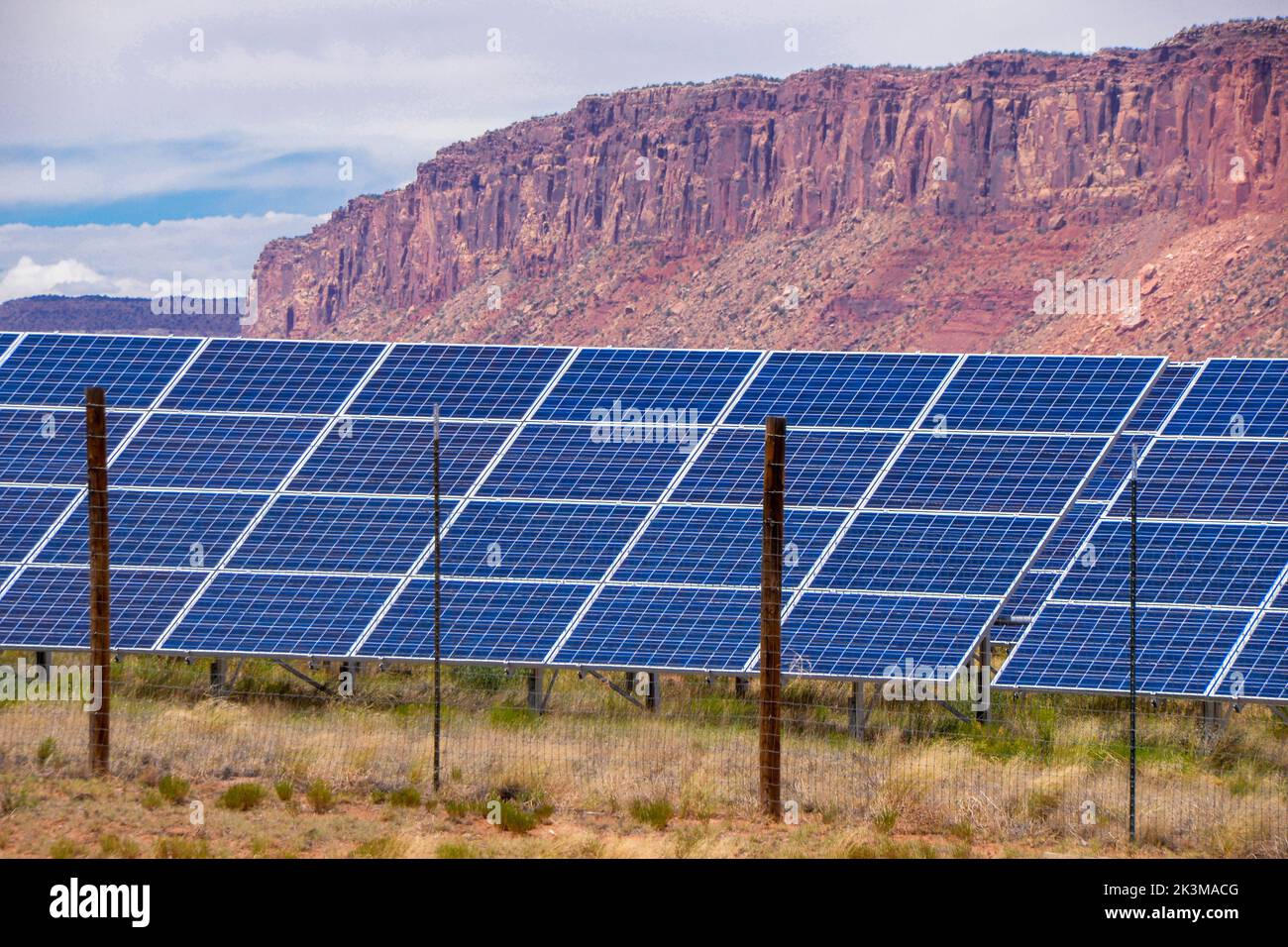 An array of solar panels facing the sun with a mountain backdrop in the ...