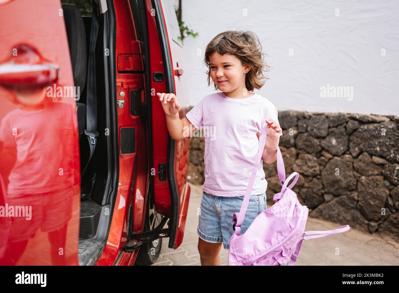 Girl in casual clothes with backpack smiling and getting into red ...