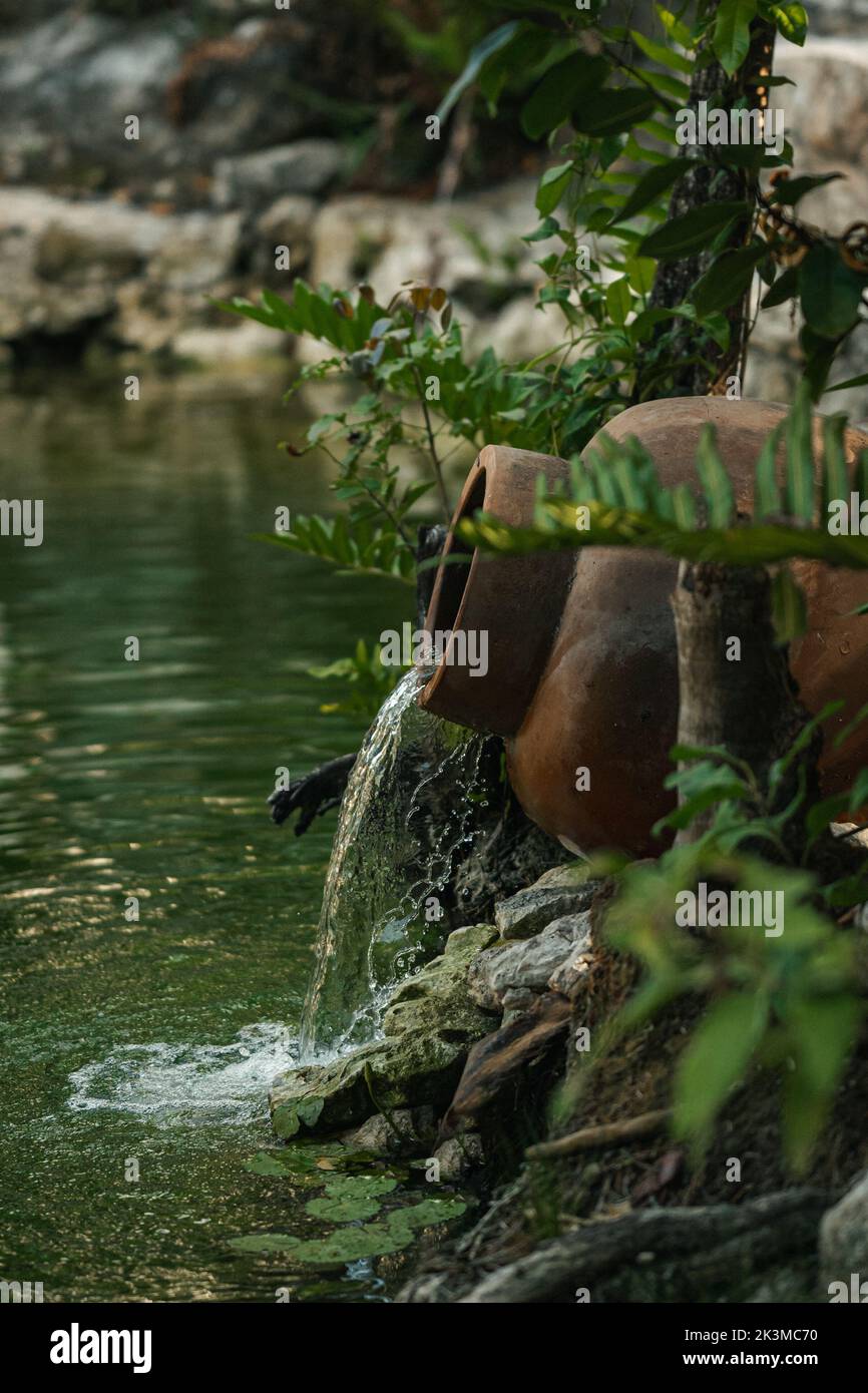 A vertical of water coming out of a decorative pot set near an ...