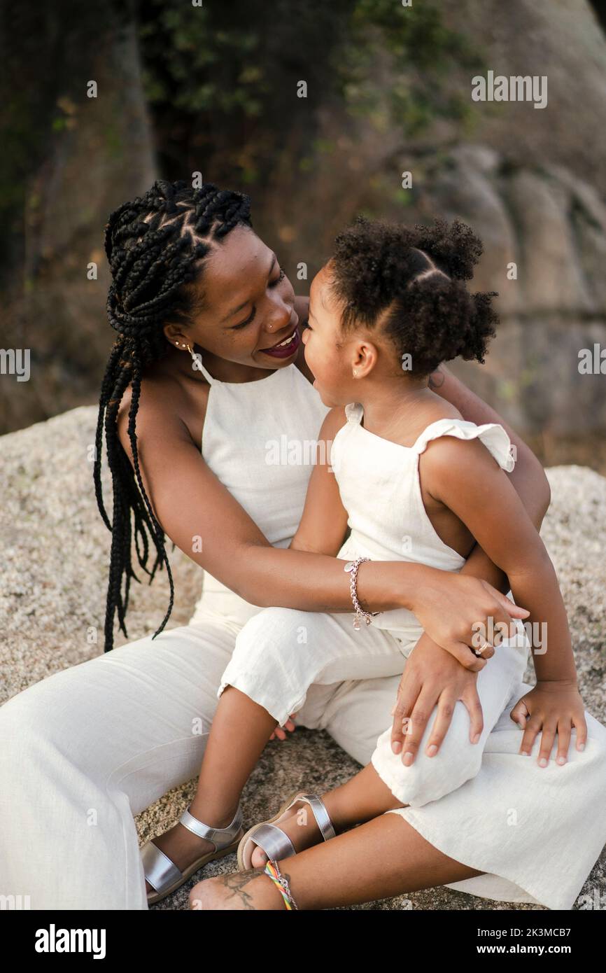 Happy black mother with Afro braids smiling and talking with cheerful ...