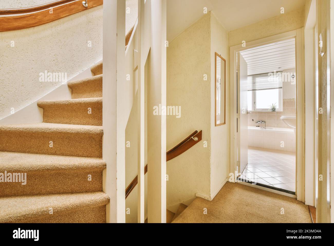 White hallway with wooden stairway leading to second floor of modern luxury apartment with ...