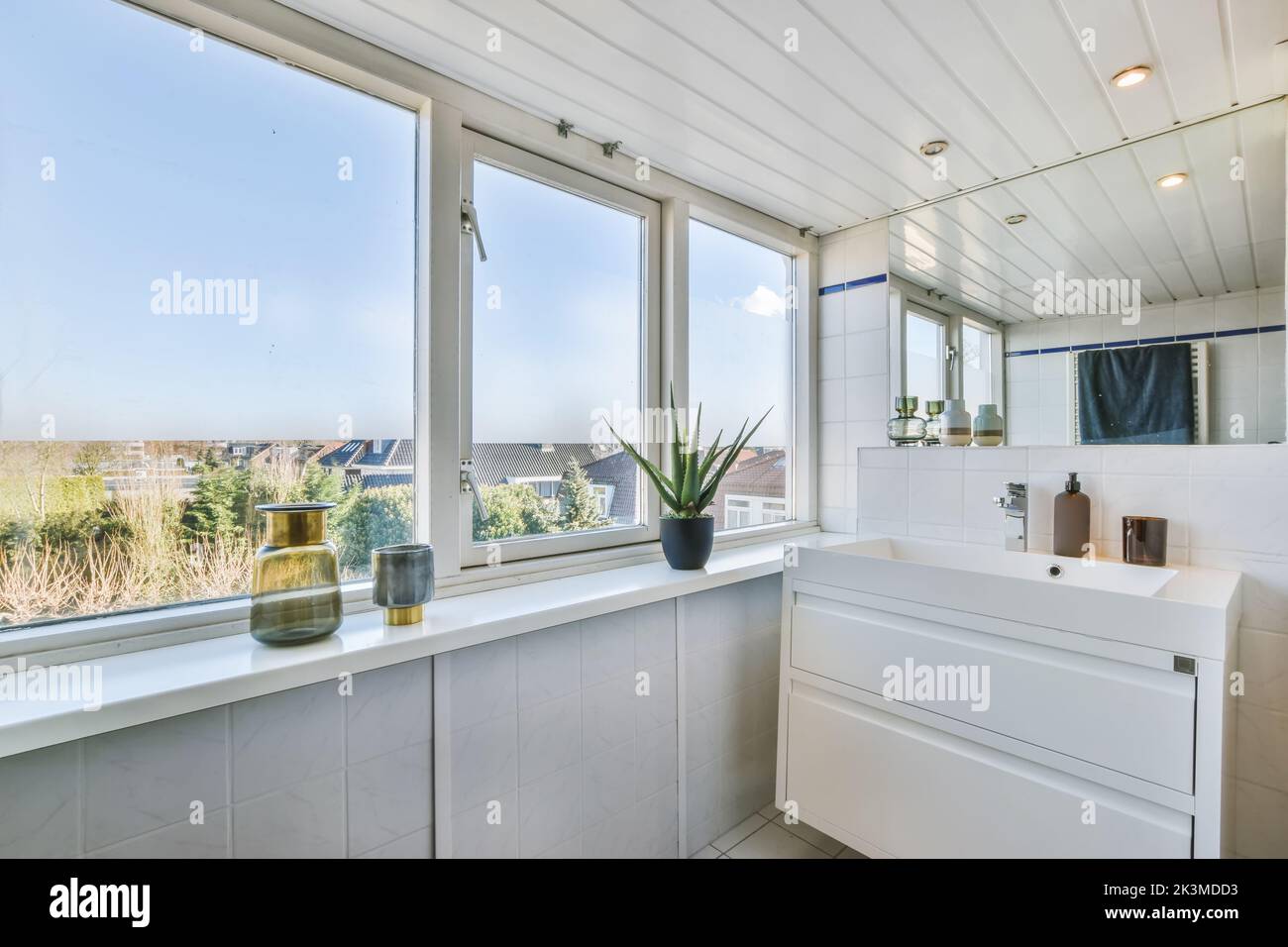 Interior of a sink next to a mirror with white walls next bright window ...