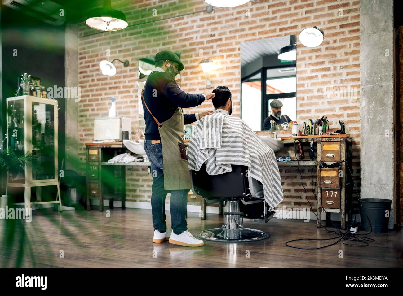 Back view male barber with comb brushing hair of unrecognizable client ...