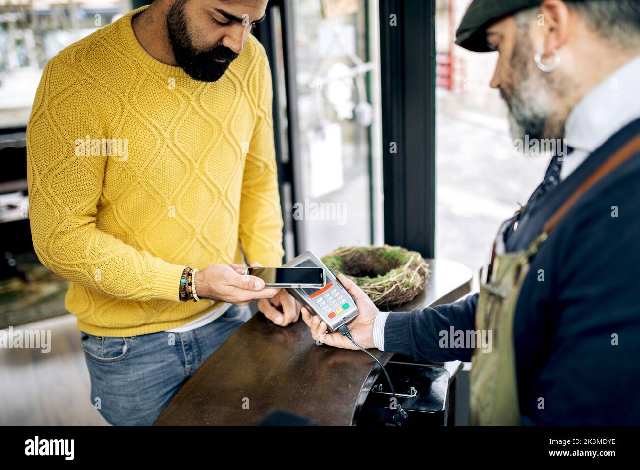 Ethnic male client making contactless paying with smartphone on POS ...