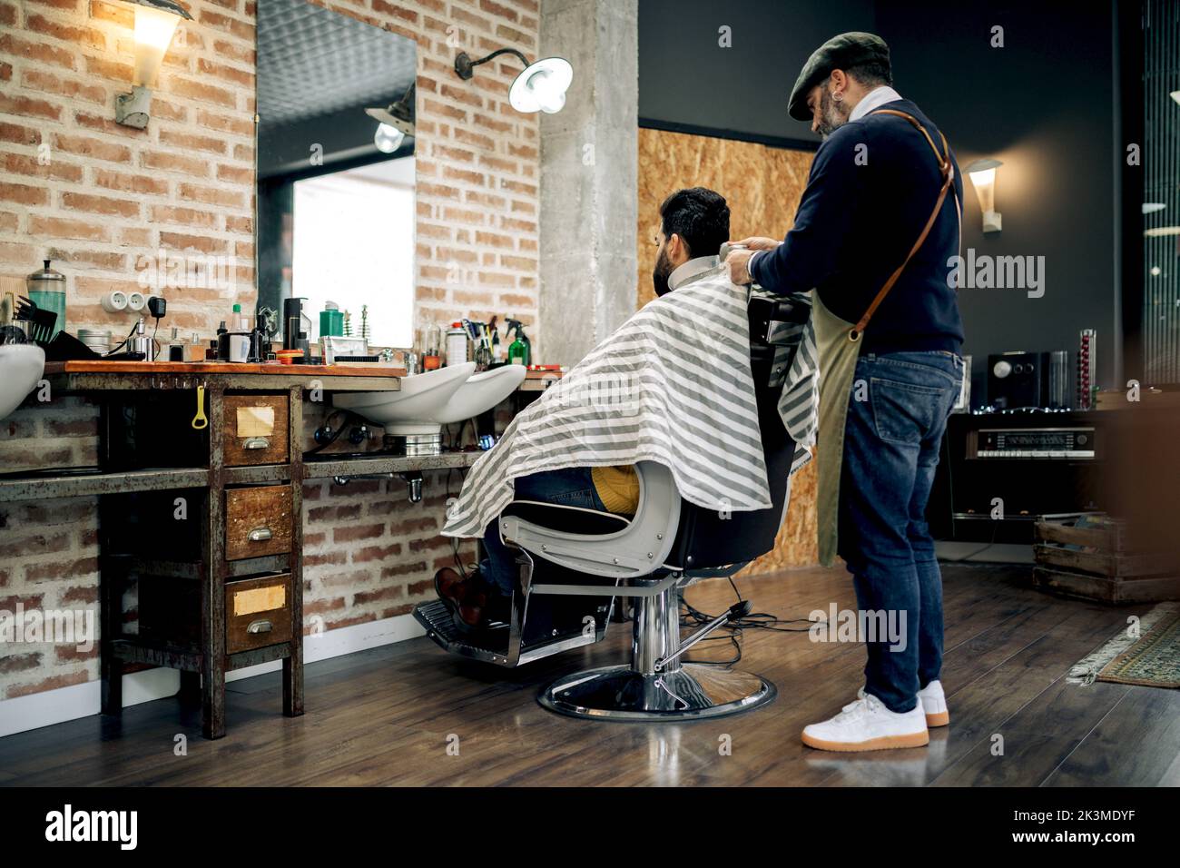 Back view male barber with comb brushing hair of unrecognizable client ...
