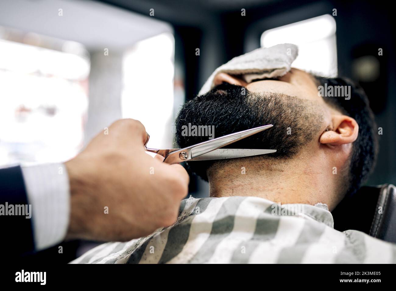 Cropped unrecognizable male barber in apron and beret cutting dark ...