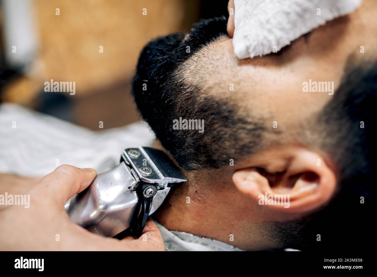 Crop unrecognizable barber using electric razor while shaving dark ...