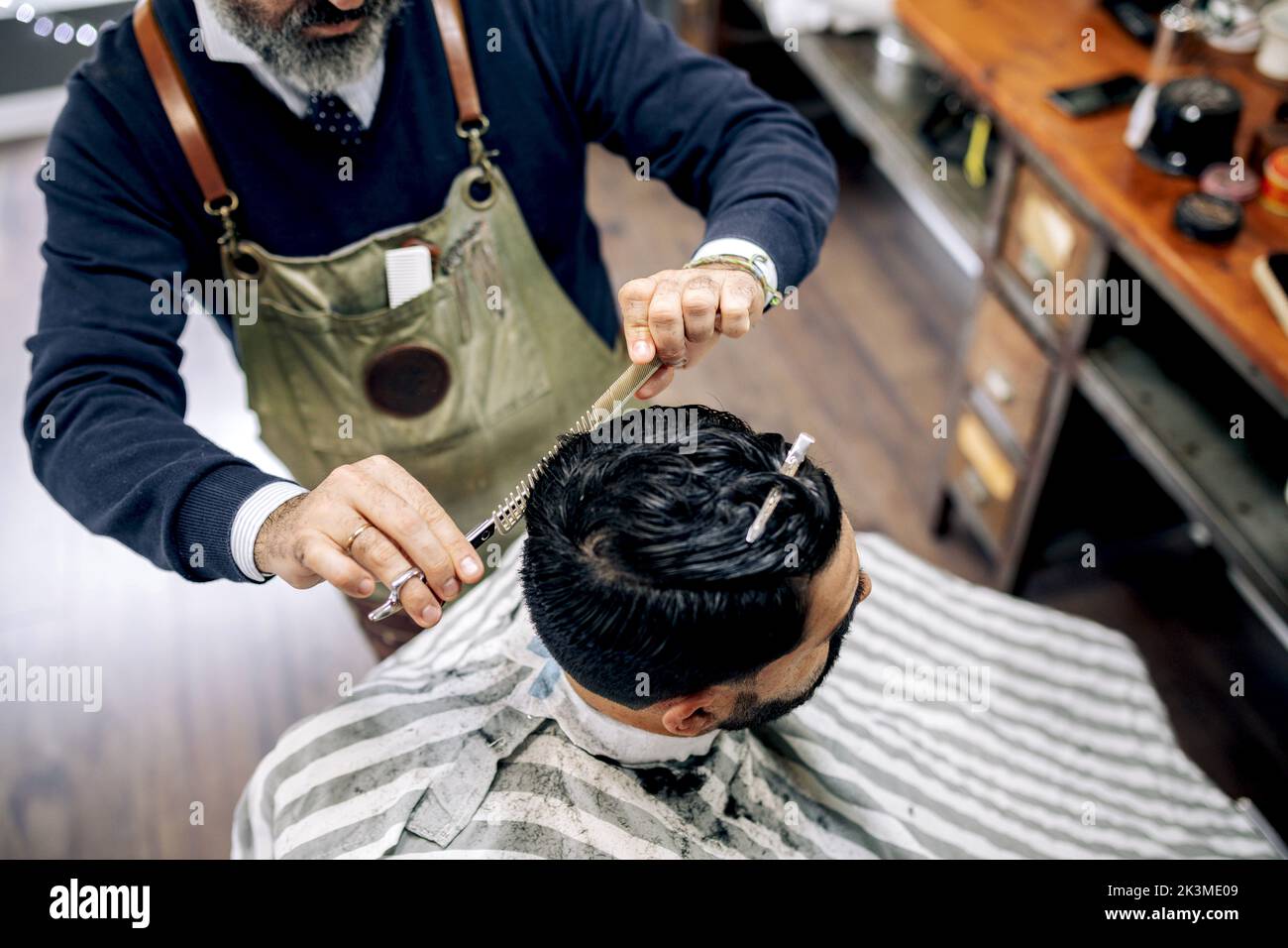 High angle of crop anonymous barber cutting hair of male customer using ...