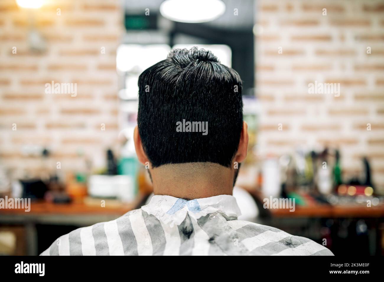 Back view of anonymous male customer with trendy hairstyle sitting in ...
