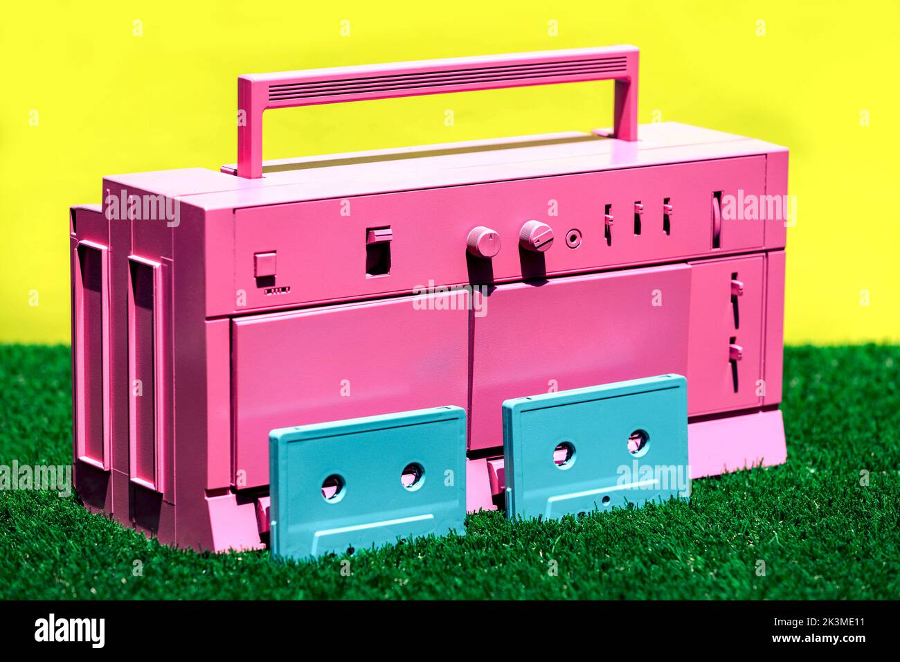 Bright pink vintage cassette player with two blue cassettes placed on ...