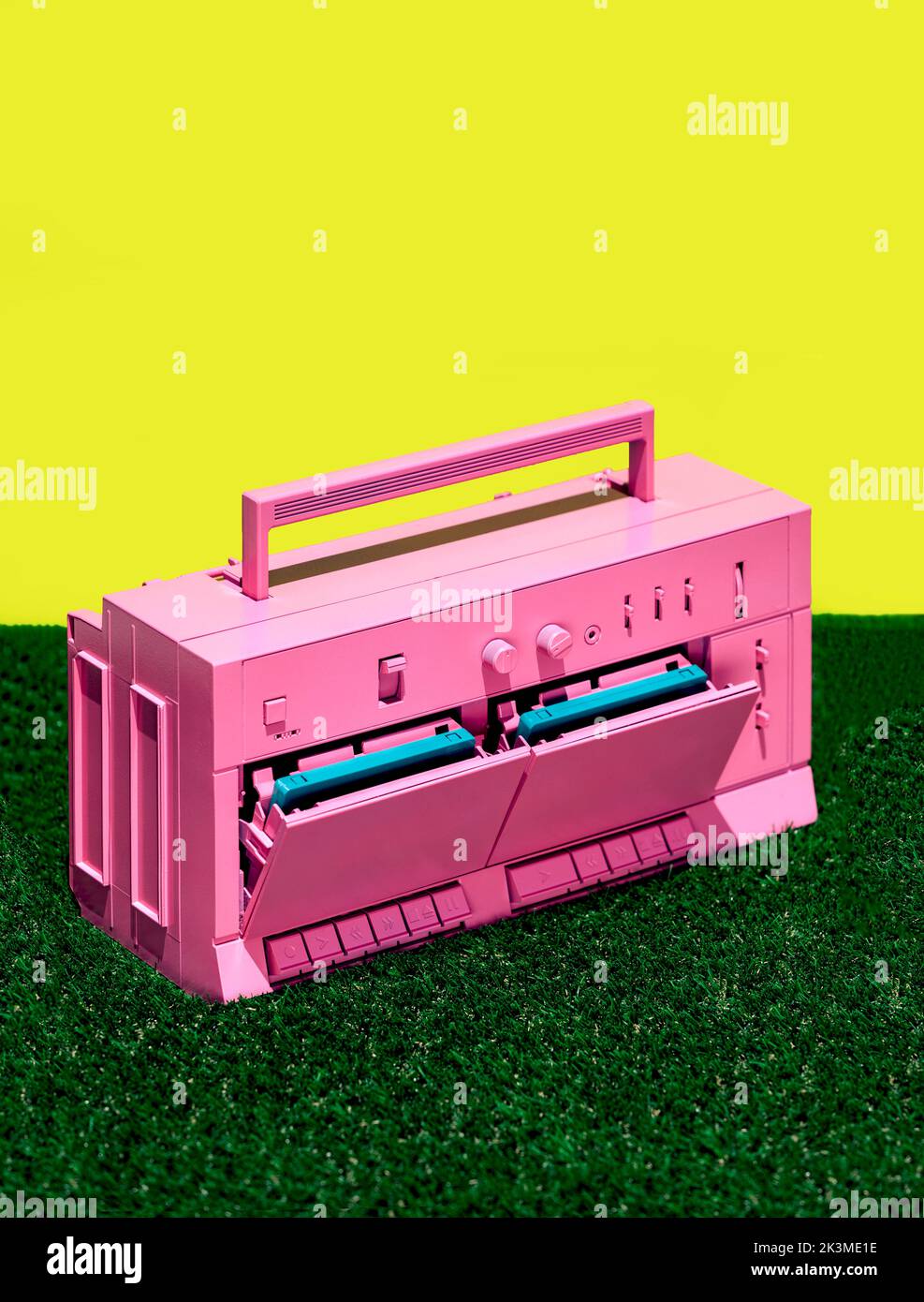 Bright pink vintage cassette player with two blue cassettes placed on ...