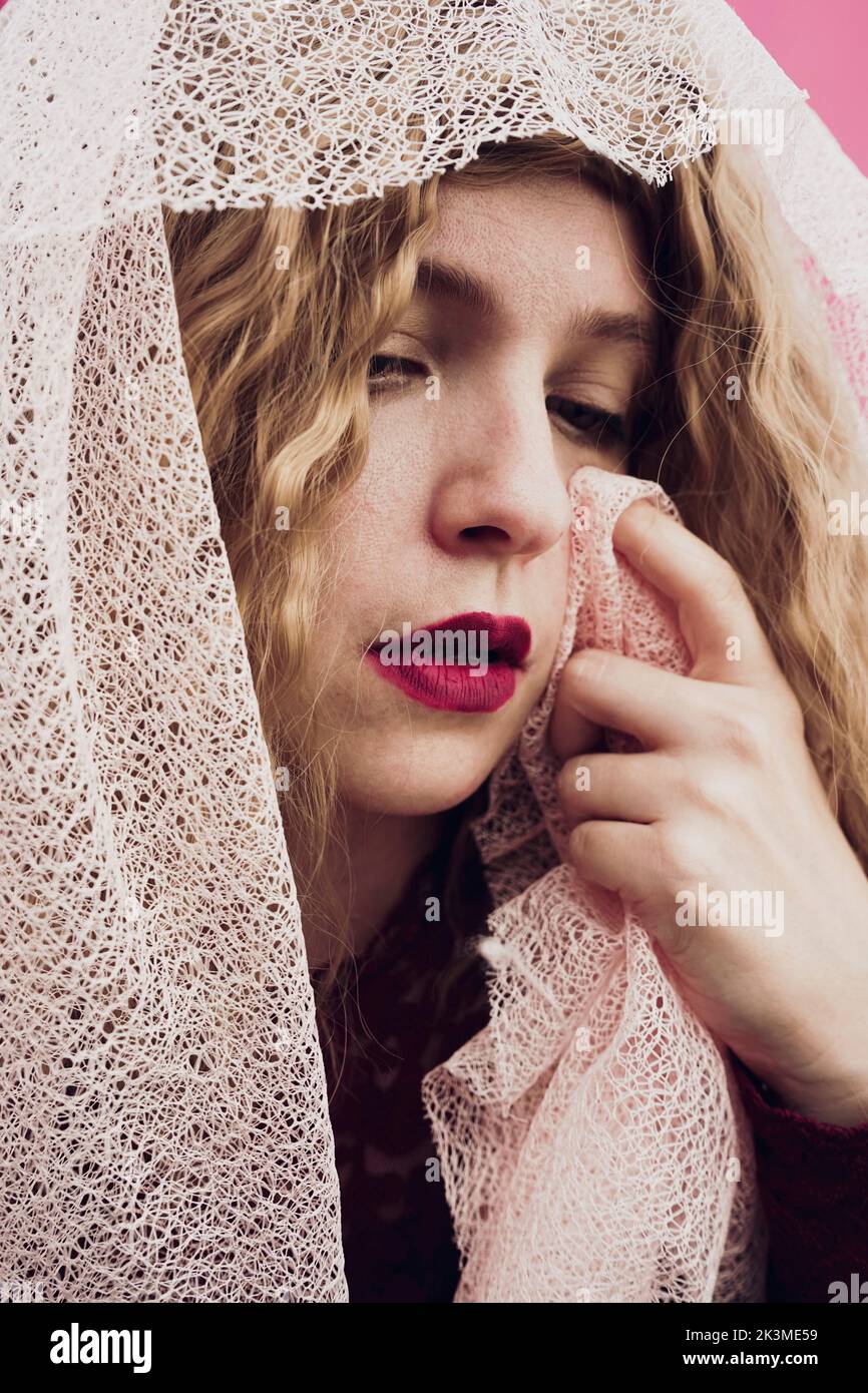 Young sad female with red lips crying and wiping tears with veil ...