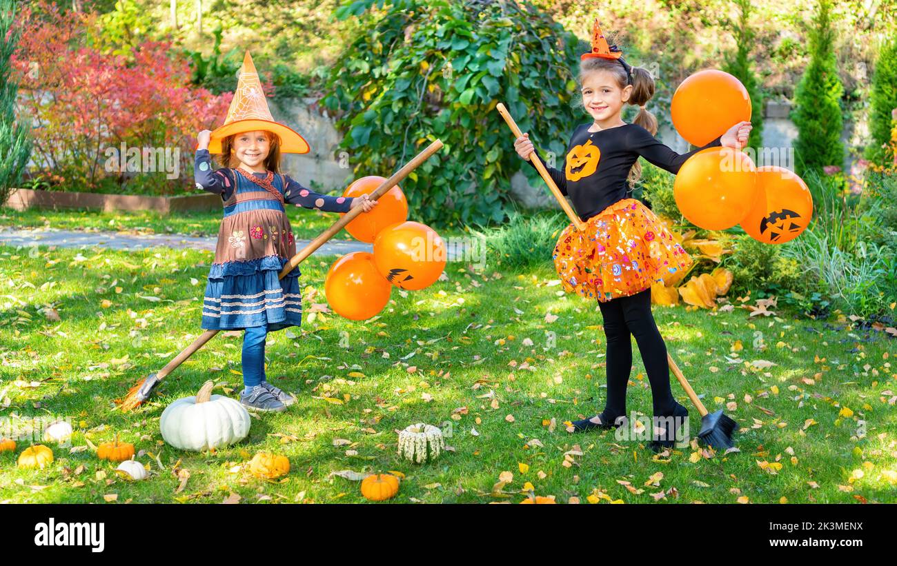 Happy kids play broomstick witches in the backyard on Halloween ...